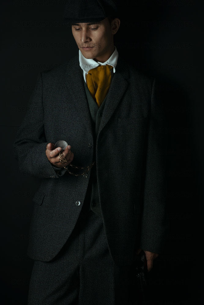 Working class Victorian man holding a watch against a black backdrop ...